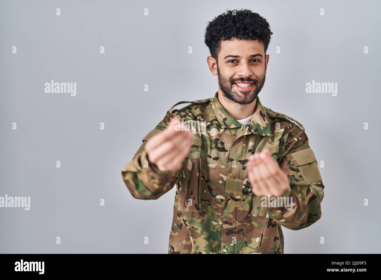 Arab man wearing camouflage army uniform doing money gesture with hands ...