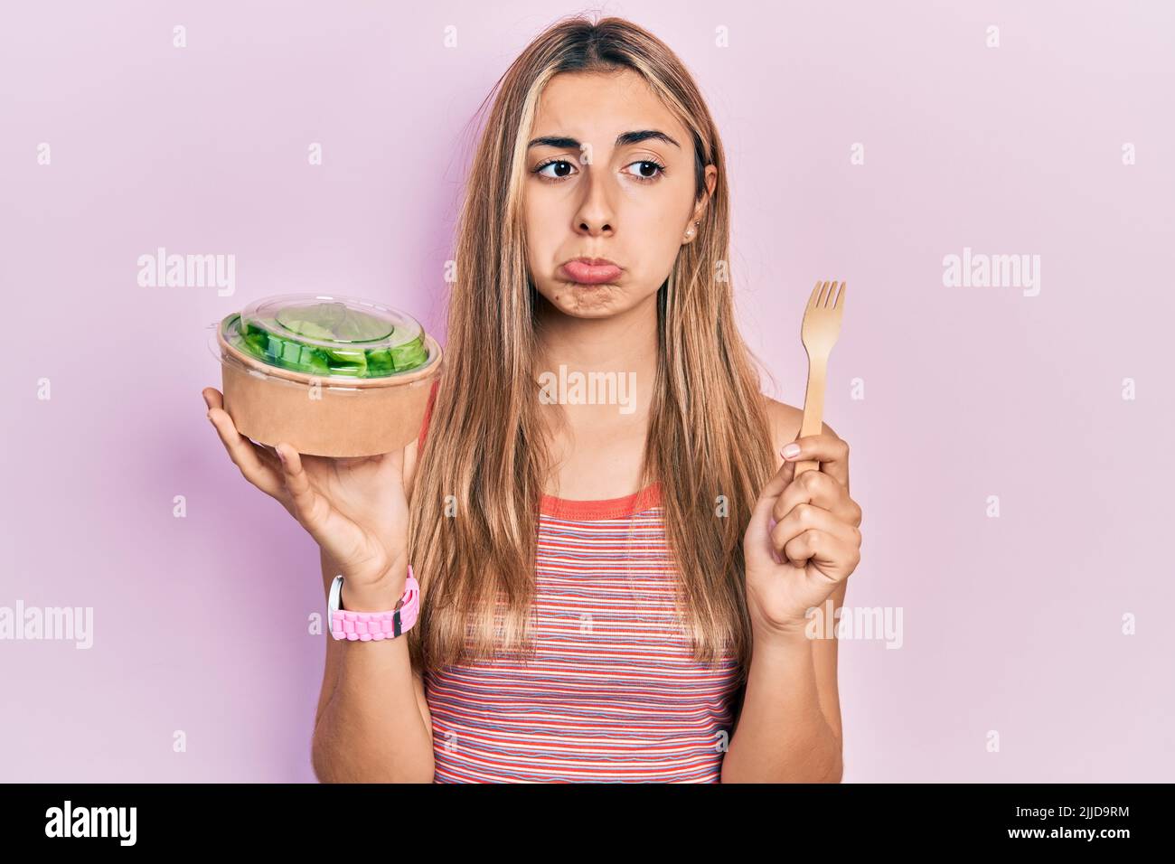 Beautiful hispanic woman eating salad depressed and worry for distress ...