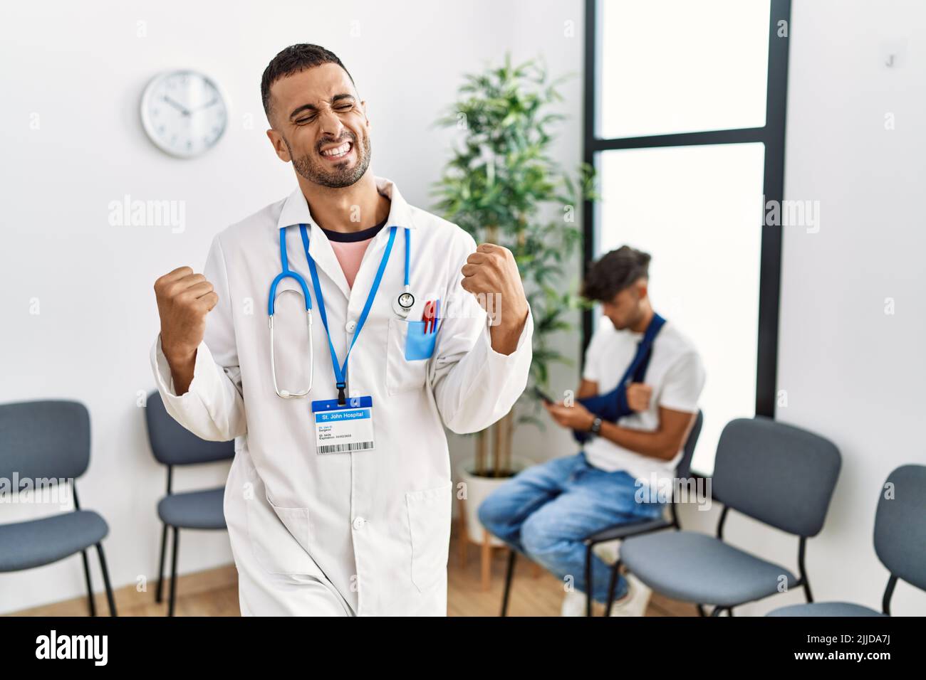 Hispanic doctor man at waiting room with pacient with arm injury very ...