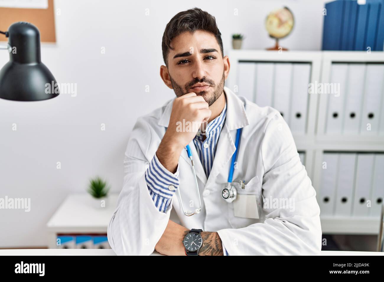 Handsome hispanic man working as doctor at medical consultation Stock ...