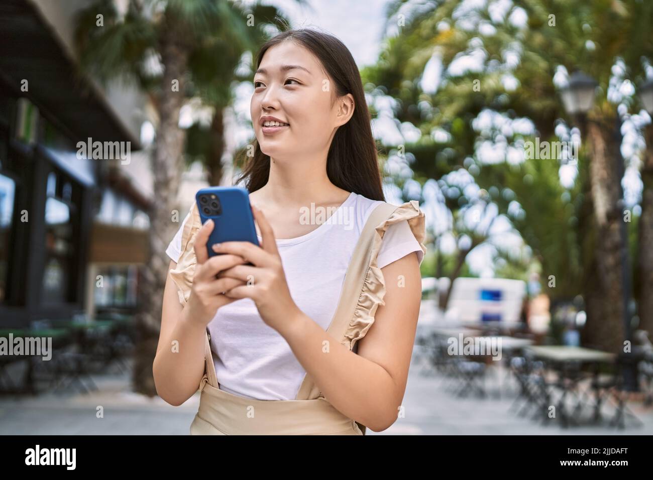 Young chinese girl smiling happy using smartphone at the city Stock ...