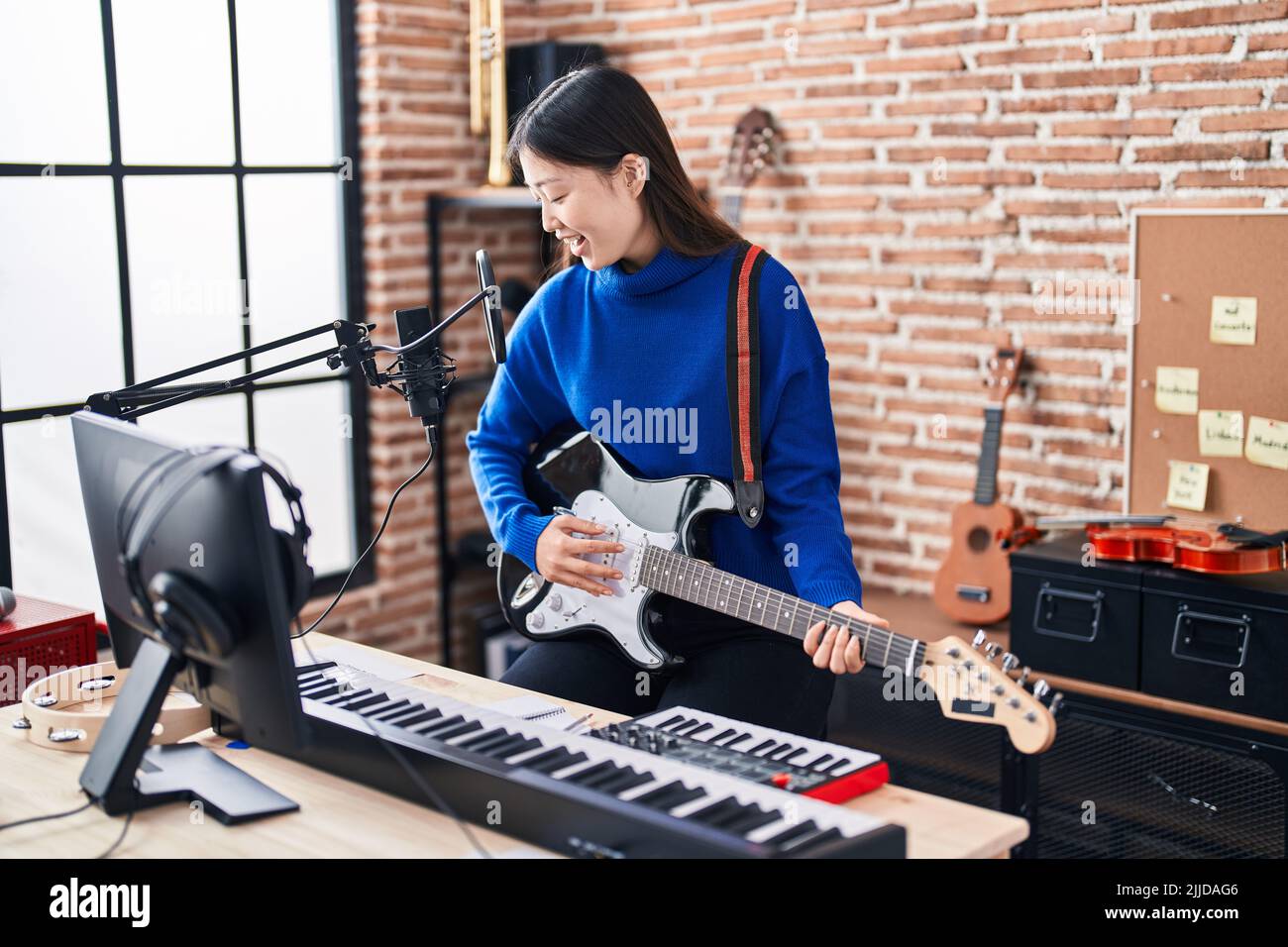 Chinese woman artist singing song playing electrical guitar at music ...