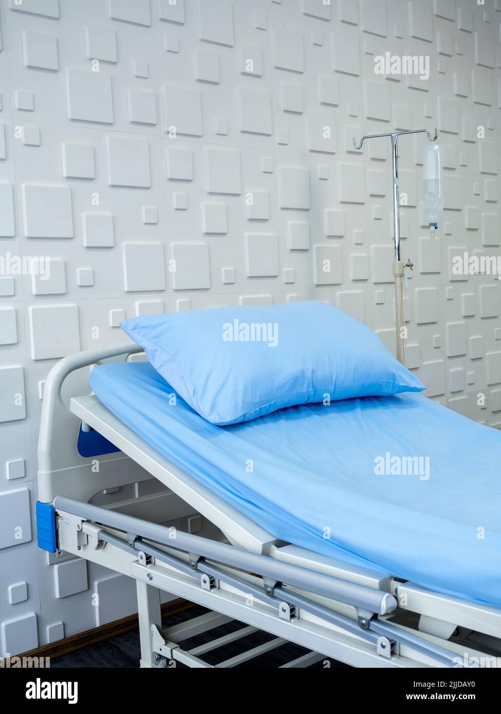 Empty patient bed in a hospital room with blue pillow and bedsheet on ...
