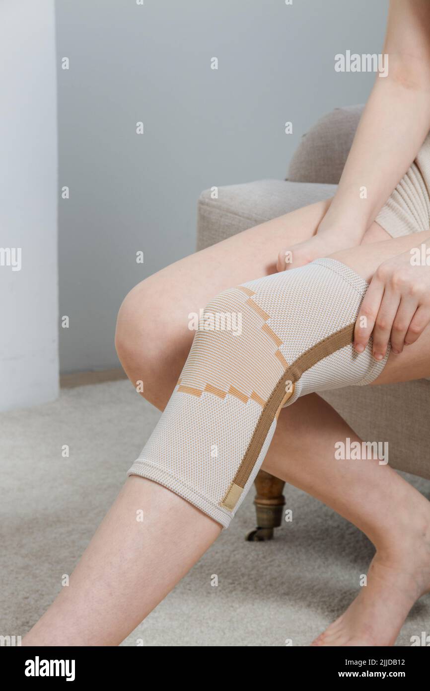 Knee support brace on a woman leg. girl in an orthosis in the interior ...