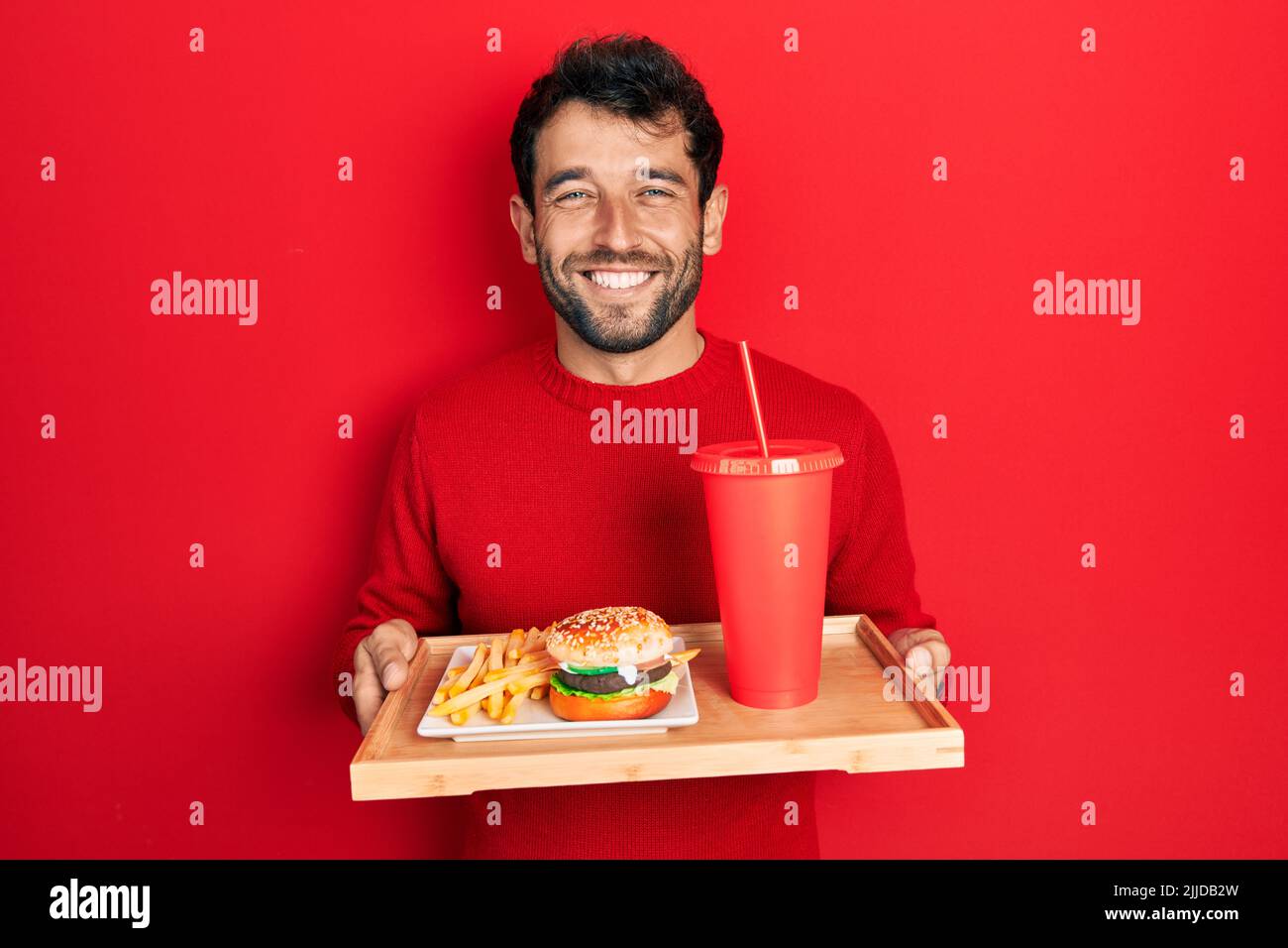 Handsome man with beard eating a tasty classic burger with fries and ...
