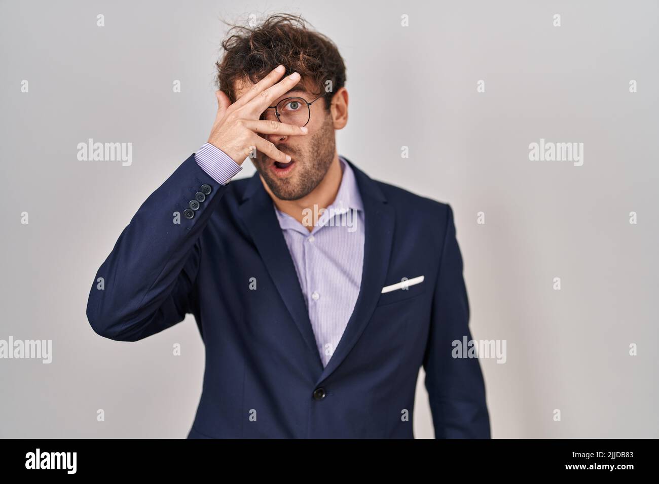 Hispanic business man wearing glasses peeking in shock covering face ...