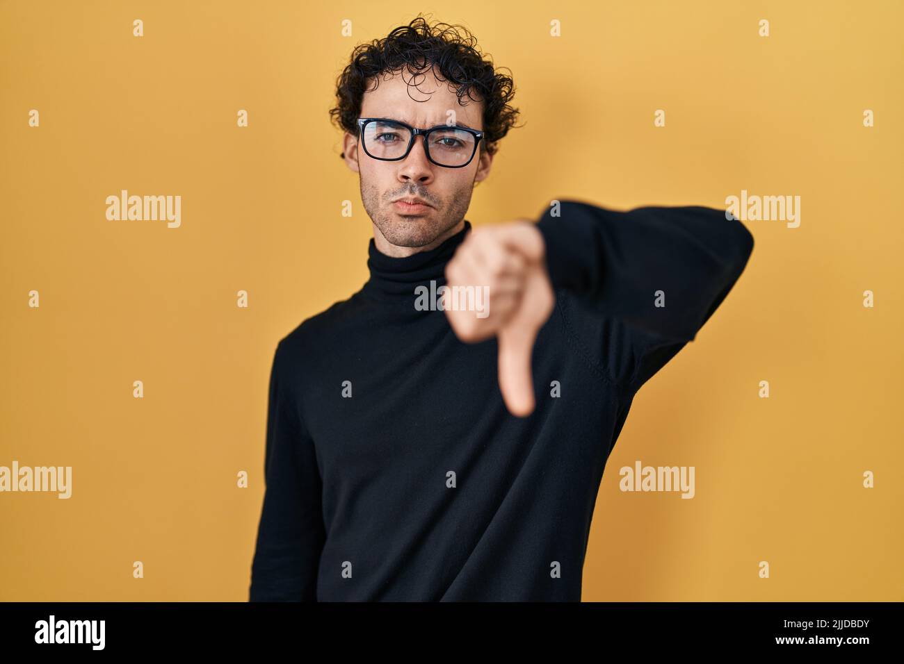 Hispanic man standing over yellow background looking unhappy and angry ...