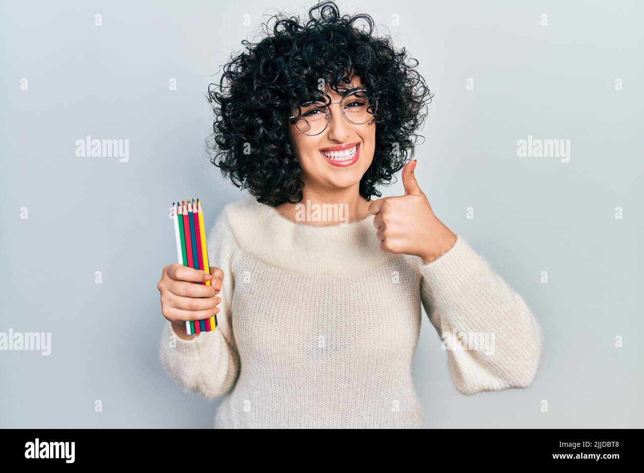 Young middle east woman holding colored pencils smiling happy and ...