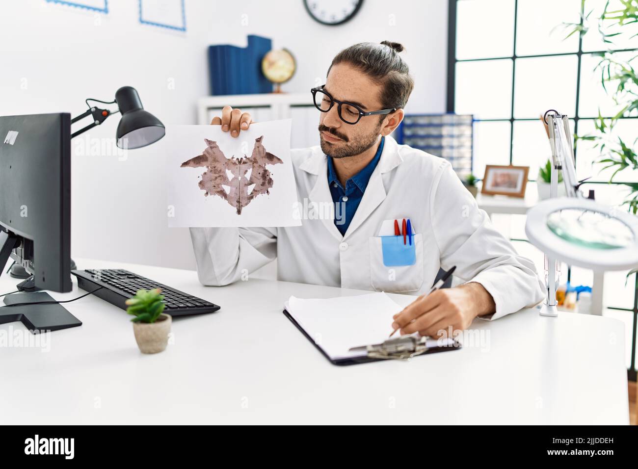 Handsome hispanic man working as psychologist showing rorschach test at ...