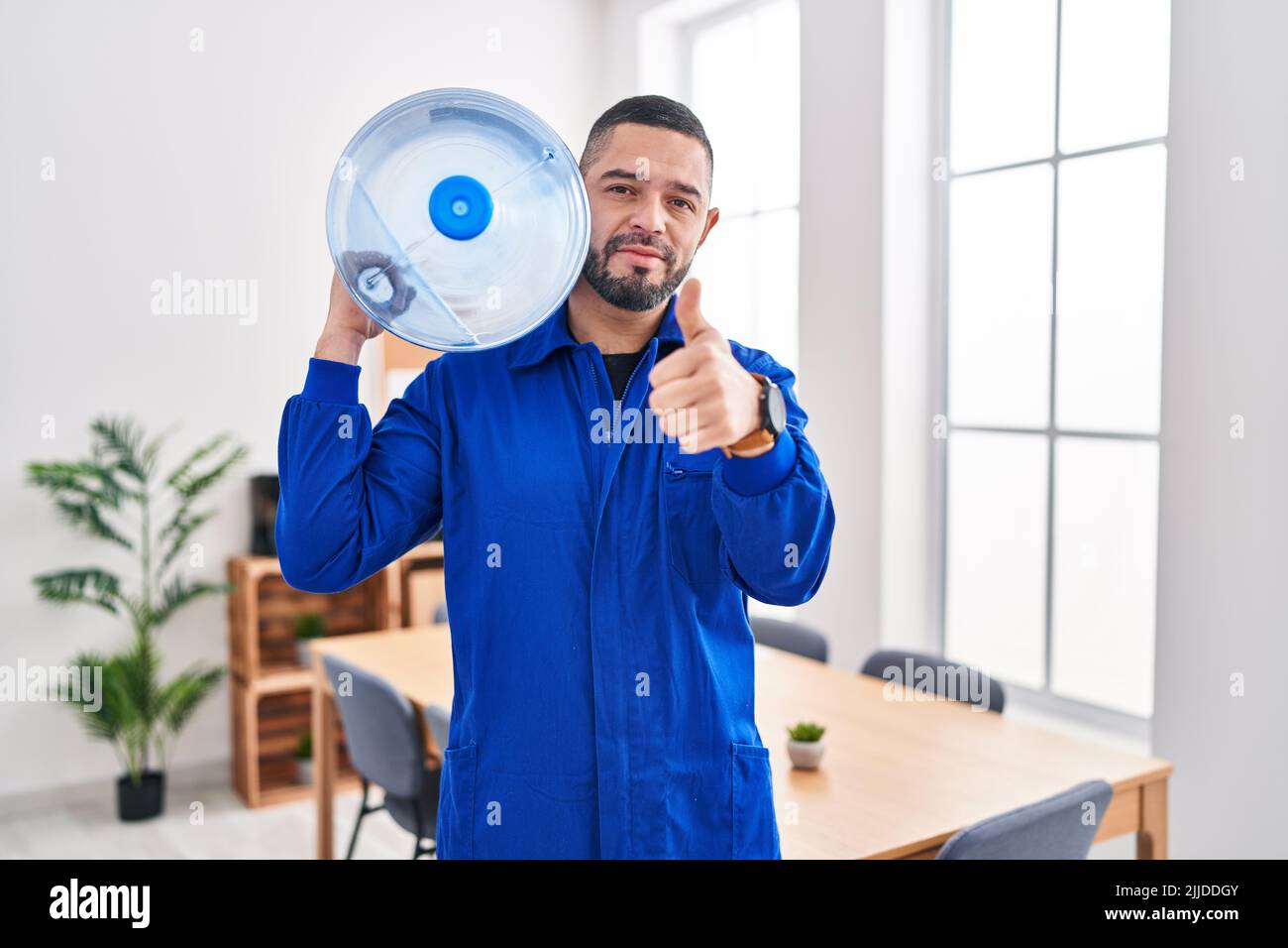 Hispanic service man holding a gallon bottle of water for delivery ...