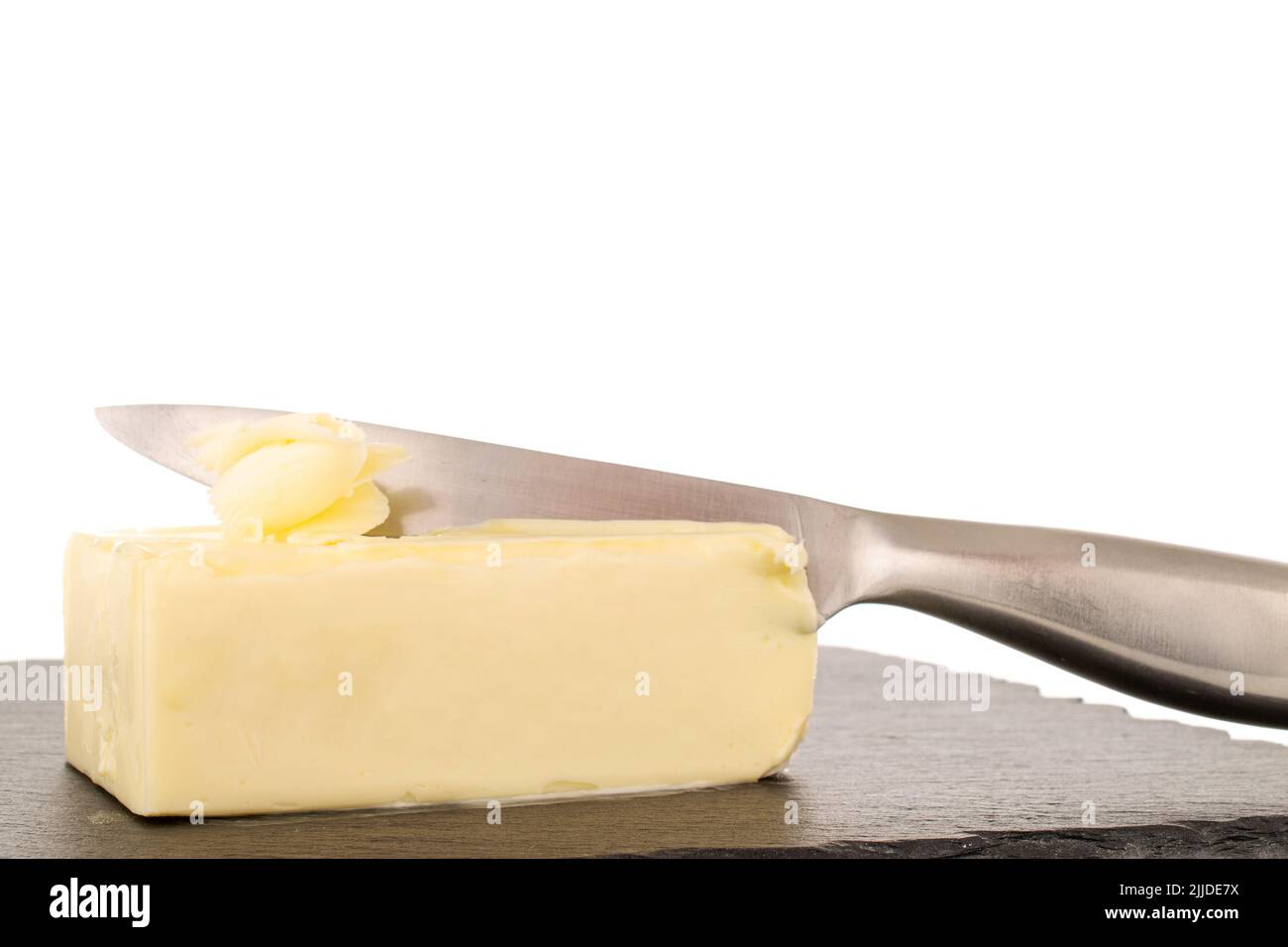 Two pieces of butter with a metal knife on a shale stone, close-up ...