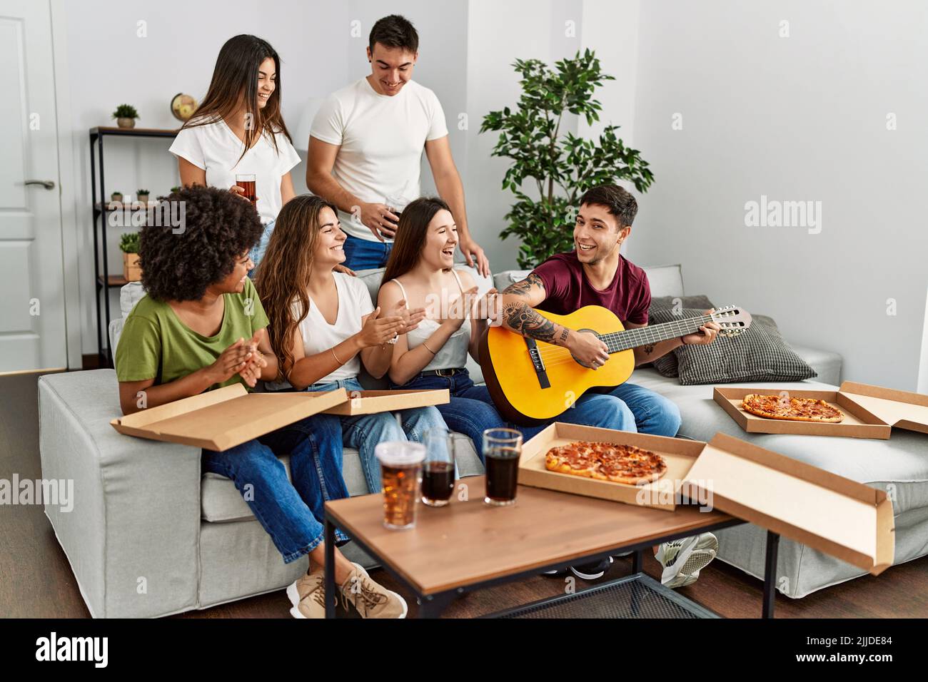 Group of young friends having party eating italian pizza and playing ...