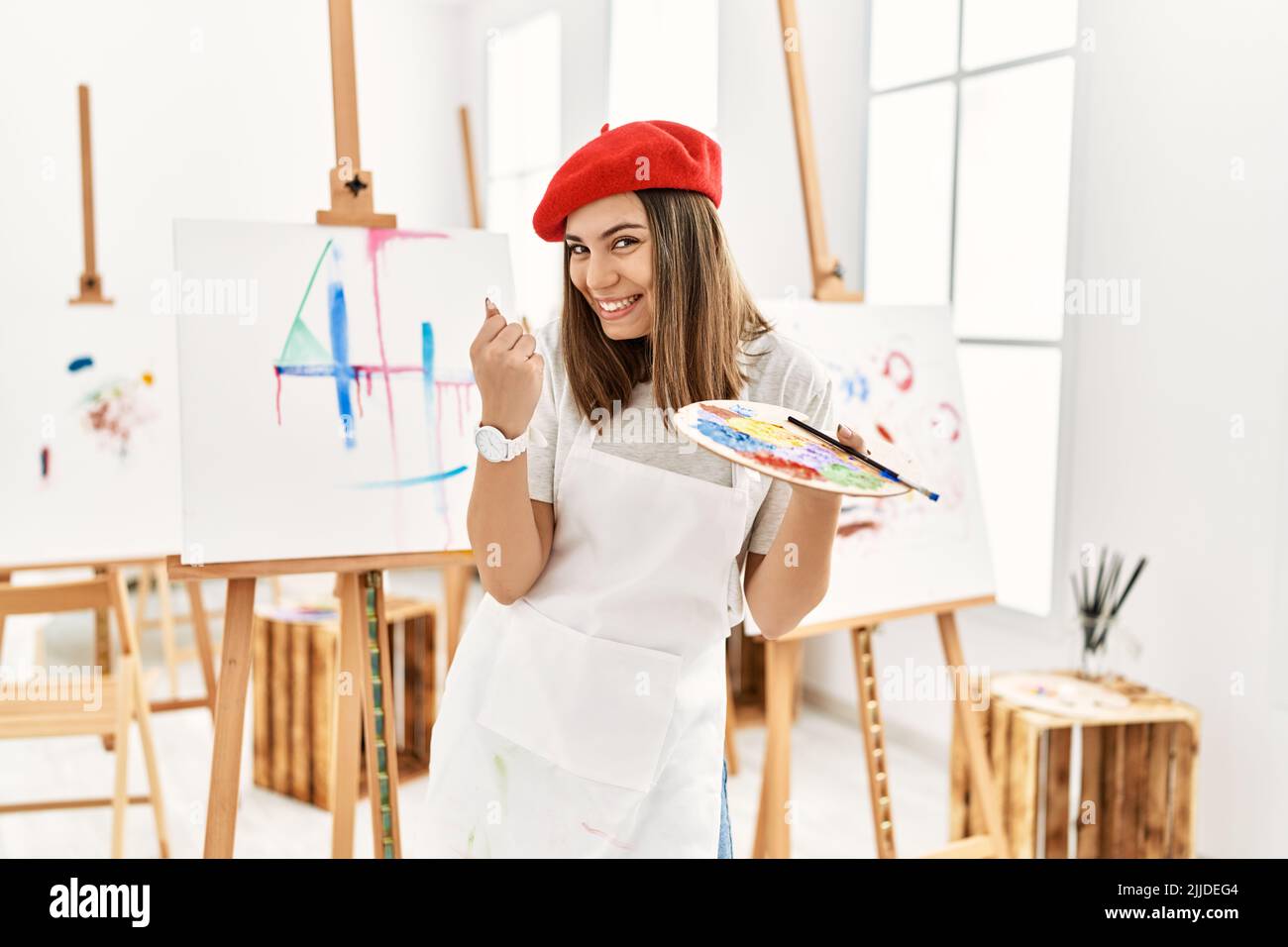 Young artist woman painting on a canvas at art studio very happy and ...