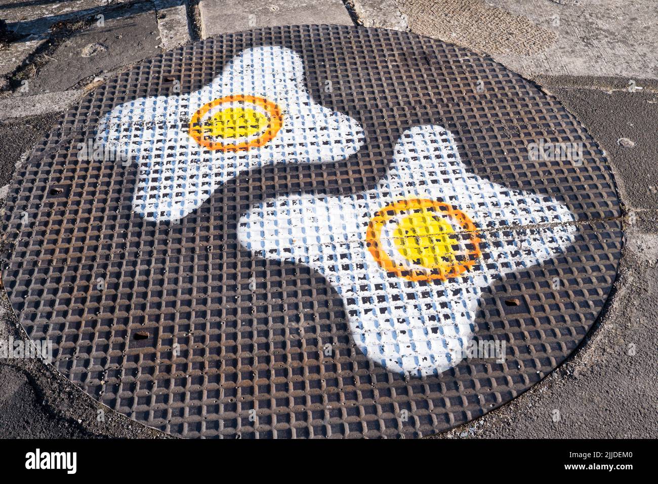 Fried egg graffiti on a manhole cover Stock Photo - Alamy