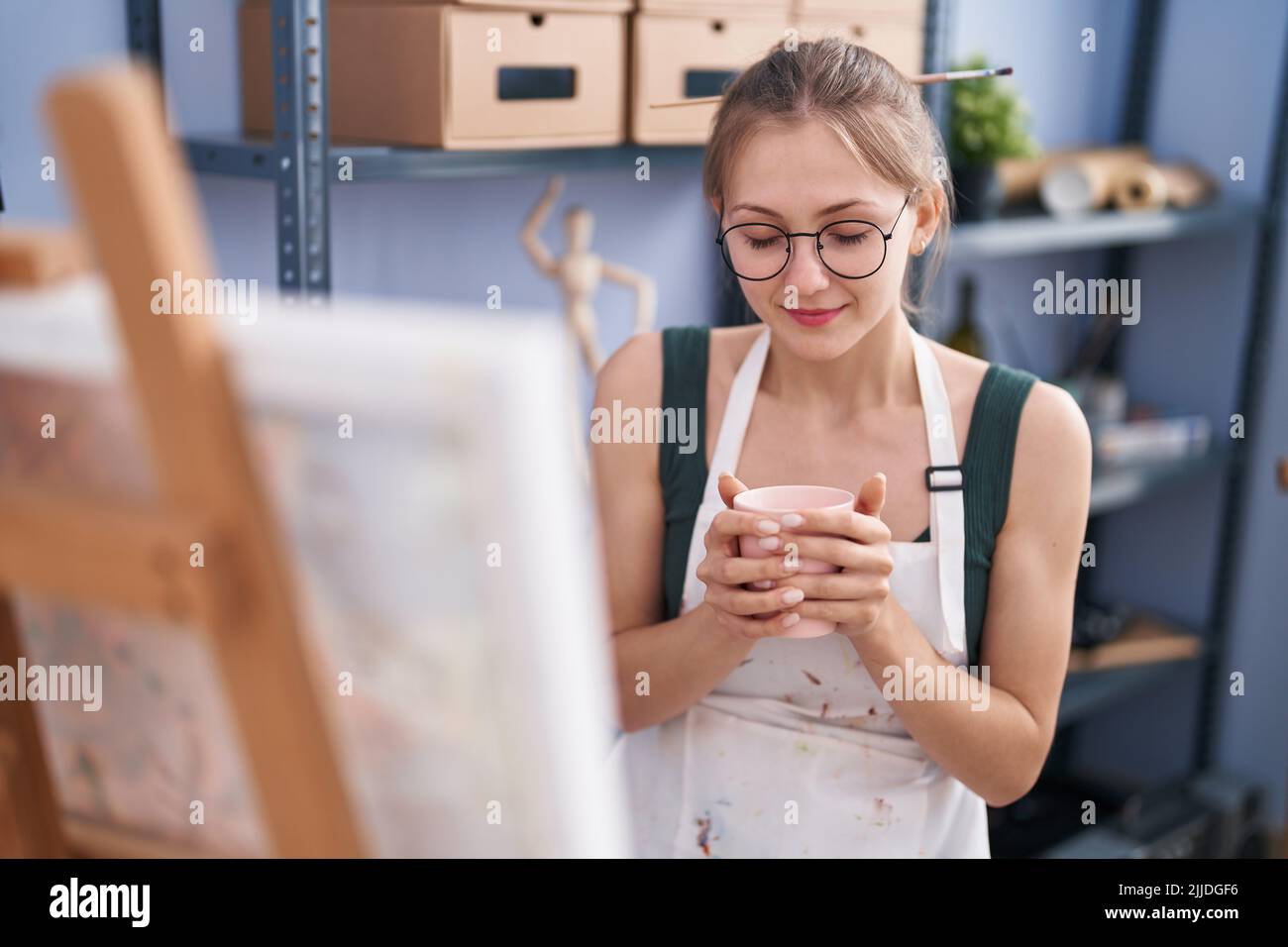 Young caucasian woman artist drinking coffee drawing at art studio ...