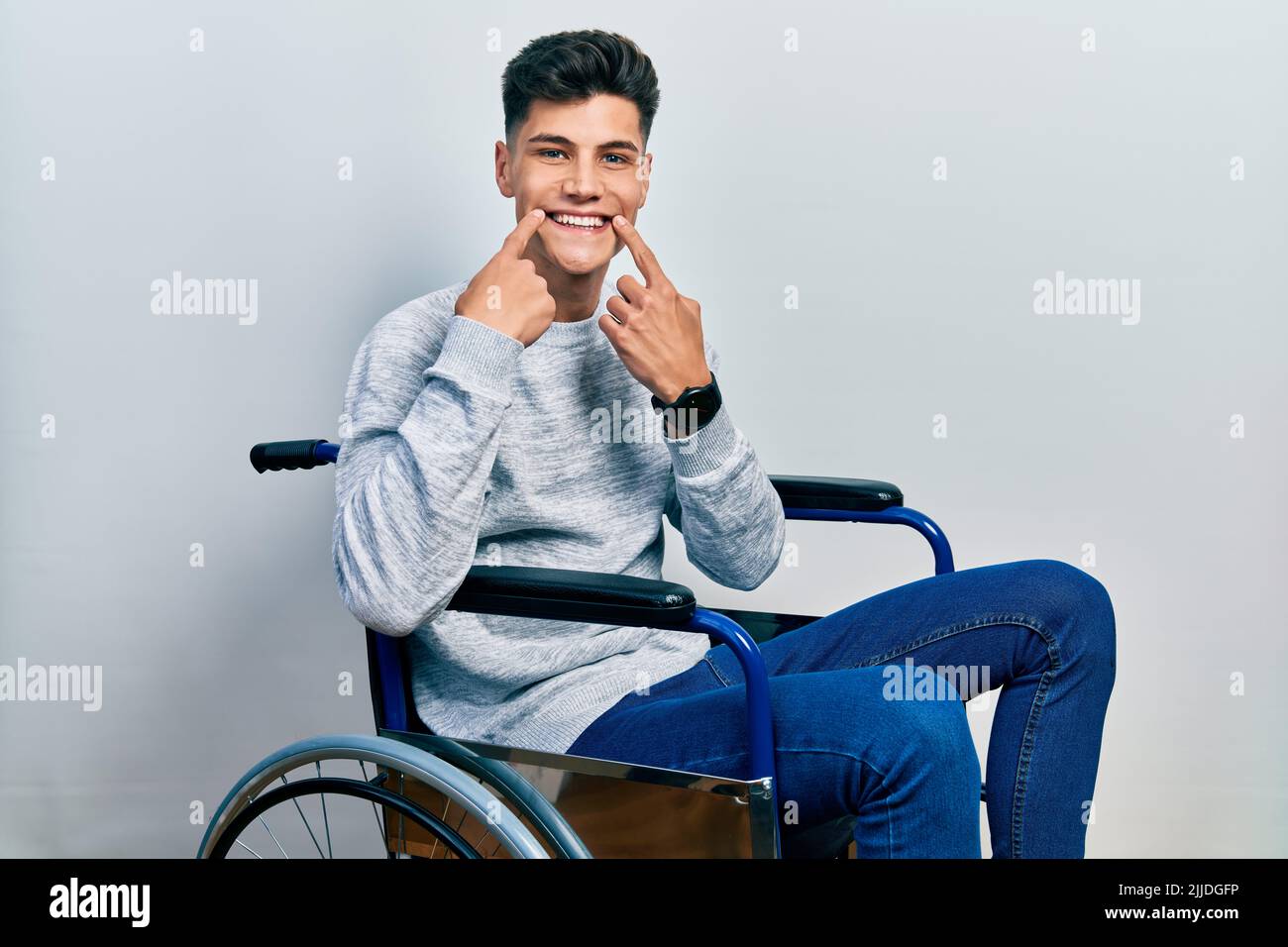 Young hispanic man sitting on wheelchair smiling with open mouth ...