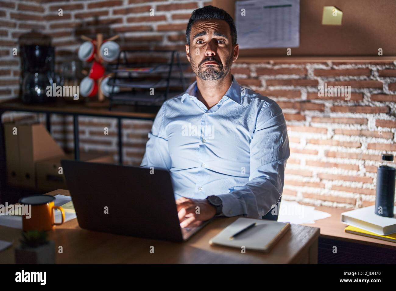 Hispanic man with beard working at the office at night depressed and ...