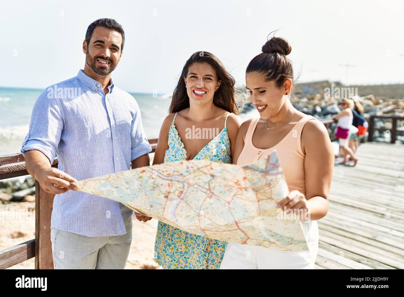 Three young hispanic friends smiling happy searching route on city map ...