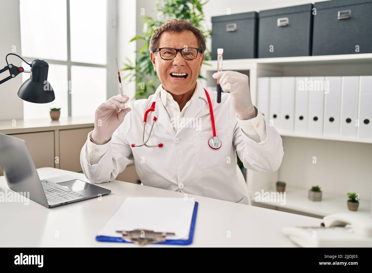 Senior doctor man holding syringe and blood sample angry and mad ...