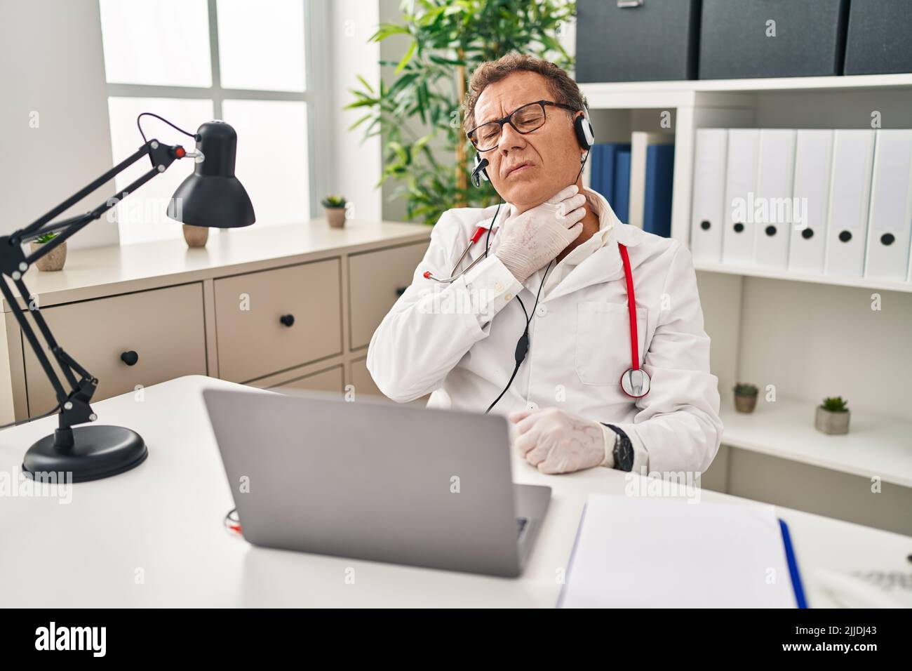 Senior doctor man working on online appointment touching painful neck ...