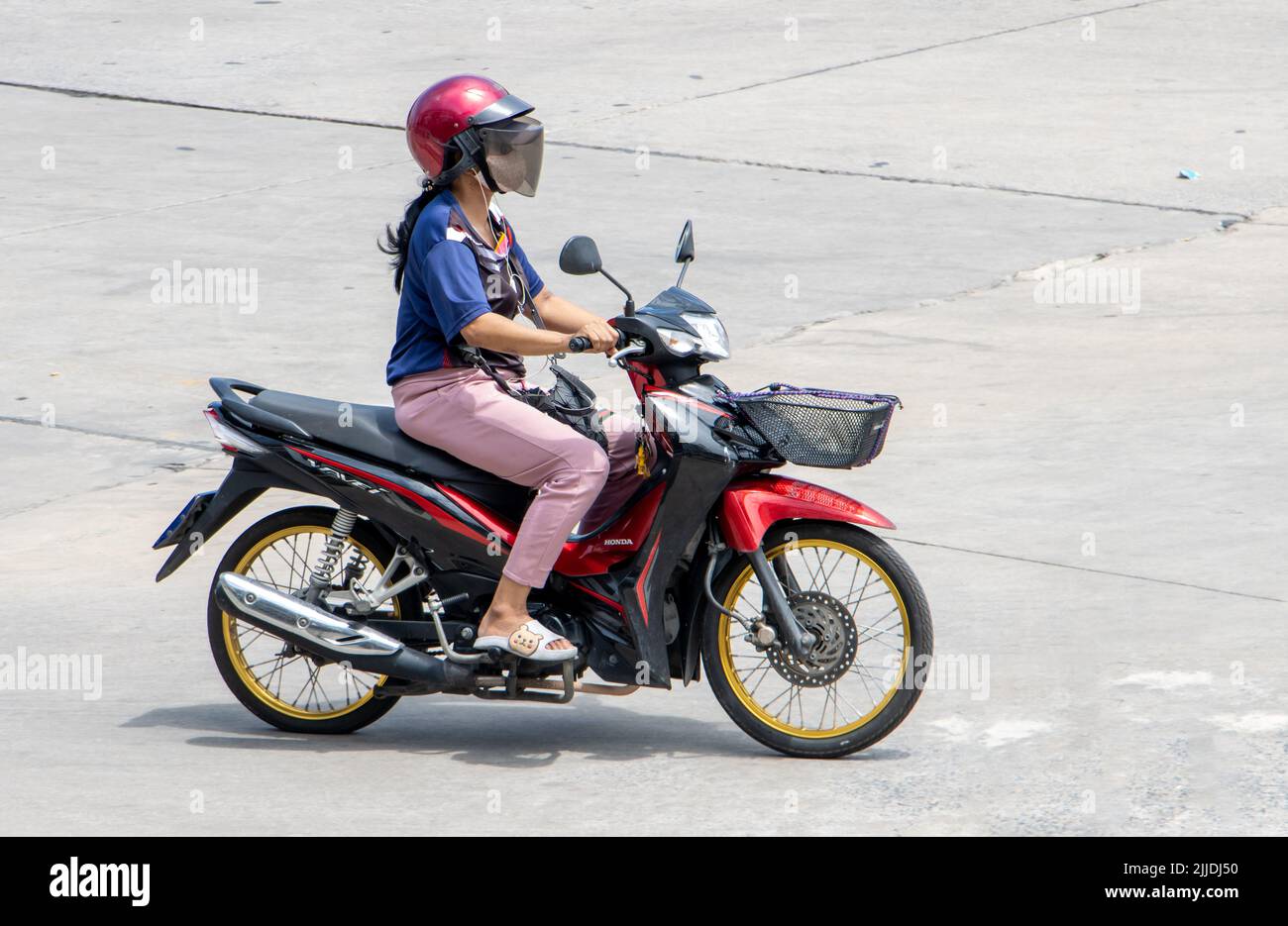 SAMUT PRAKAN, THAILAND, MAR 29 2022, A woman with helmet rides a ... SAMUT PRAKAN, THAILAND, MAR 29 2022, A woman with helmet rides a ...