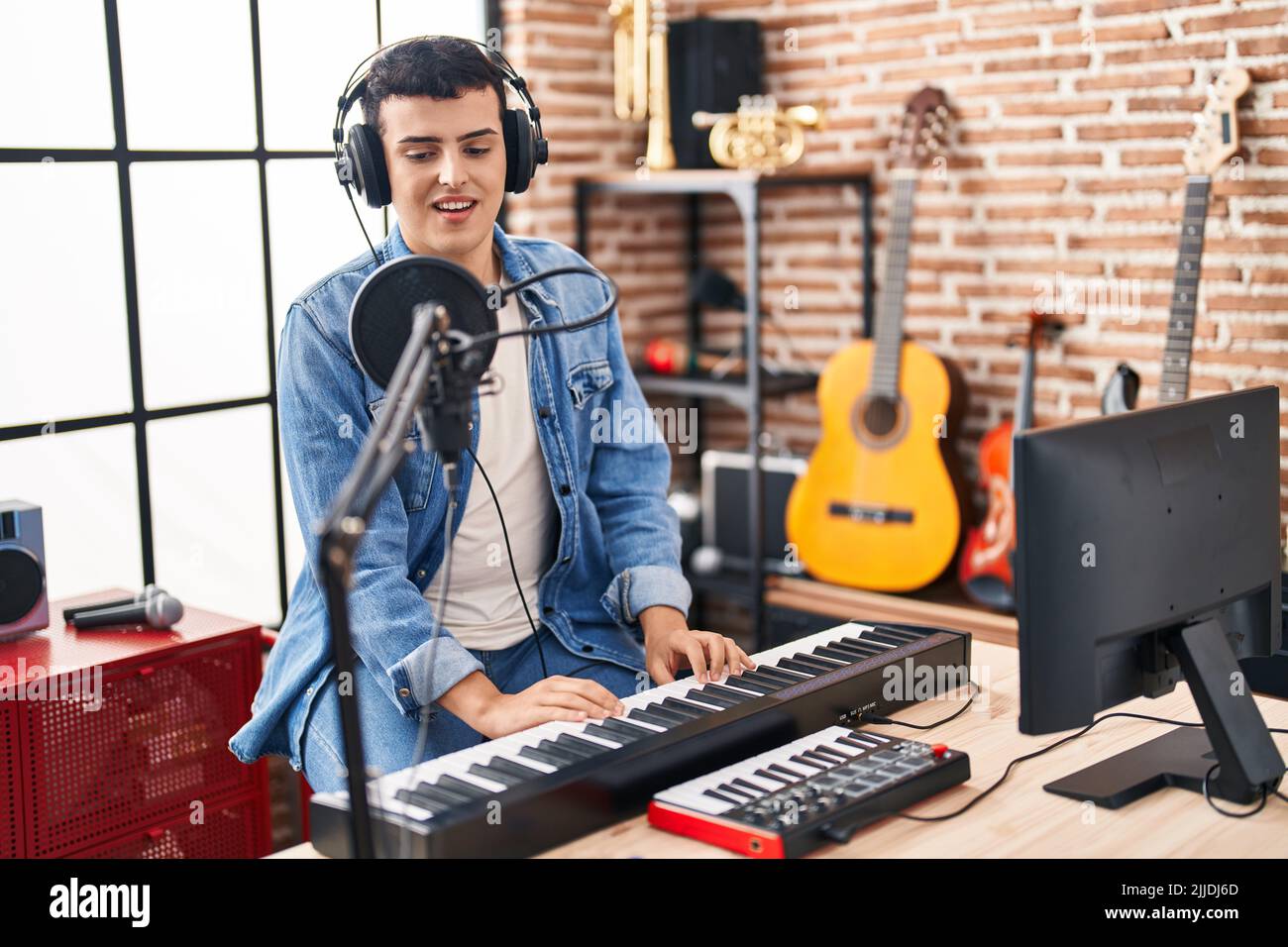 Young non binary man musician singing song playing piano keyboard at ...