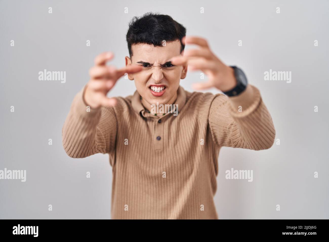 Non binary person standing over isolated background shouting frustrated ...