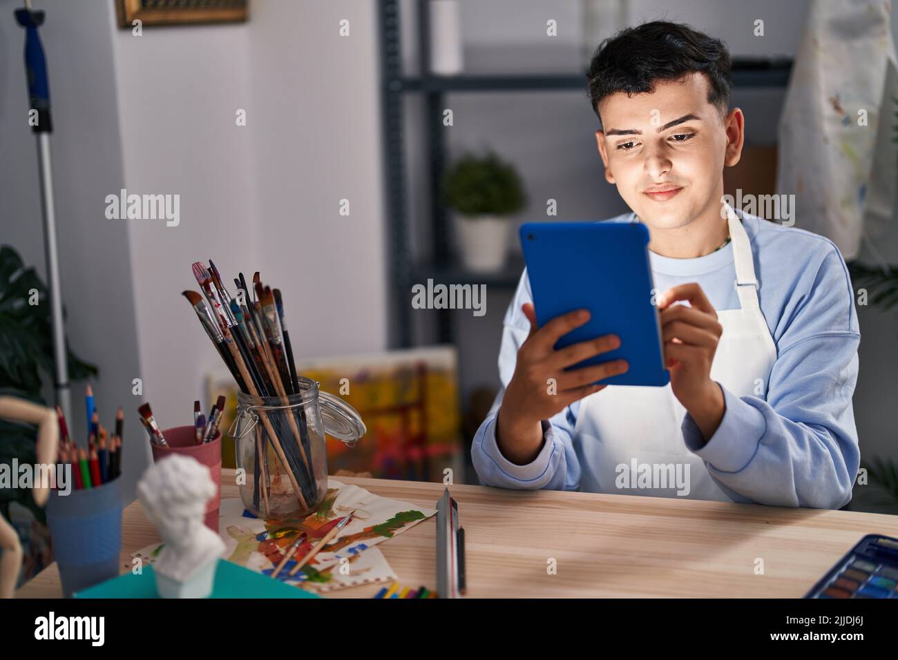 Young non binary man artist smiling confident drawing on touchpad at ...