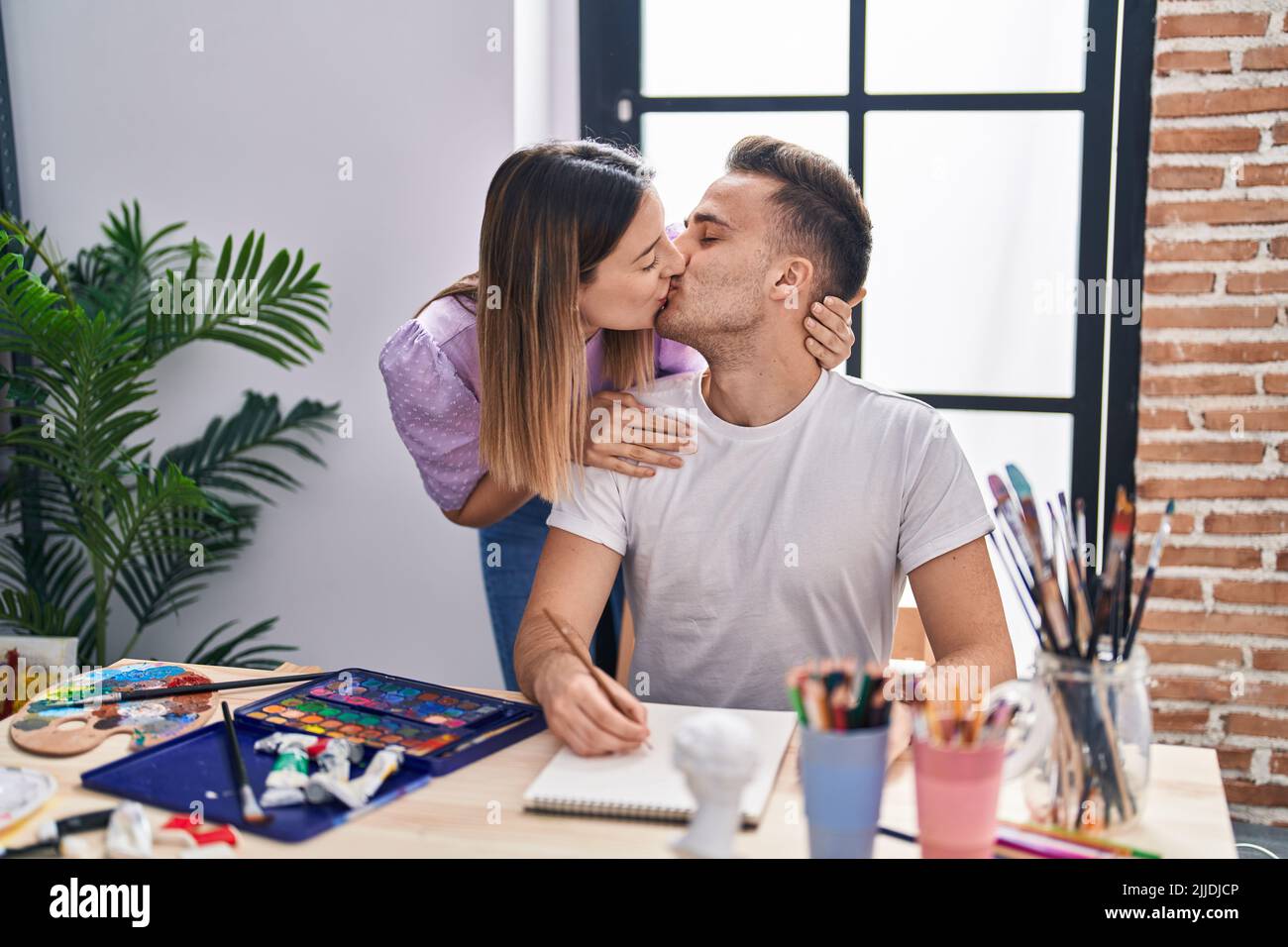 Man and woman artists couple drawing on notebook kissing at art studio Stock Photo - Alamy