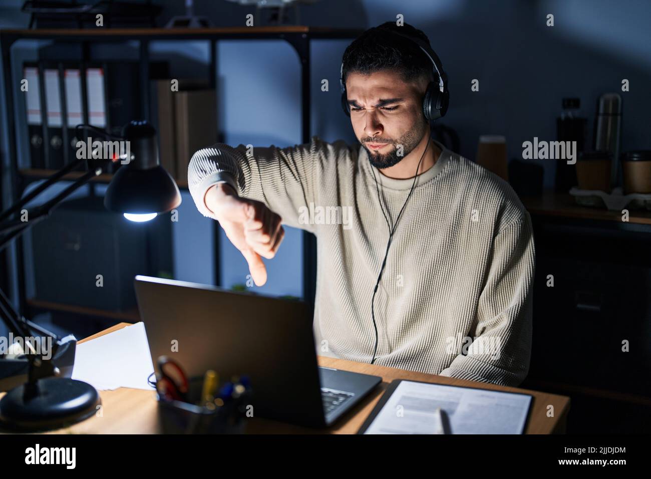 Young handsome man working using computer laptop at night looking ...