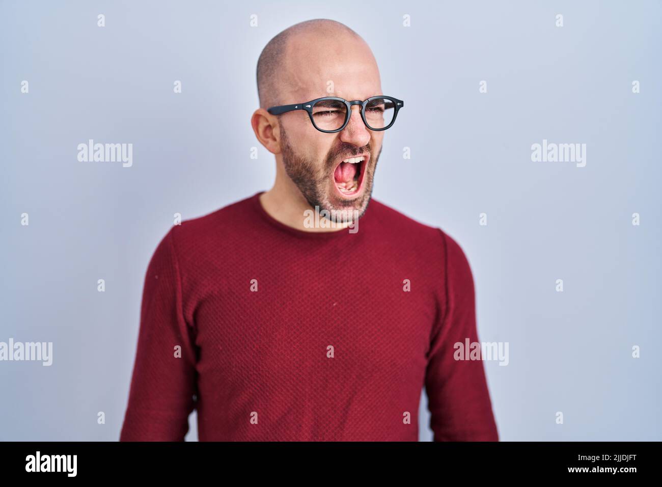 Young bald man with beard standing over white background wearing ...
