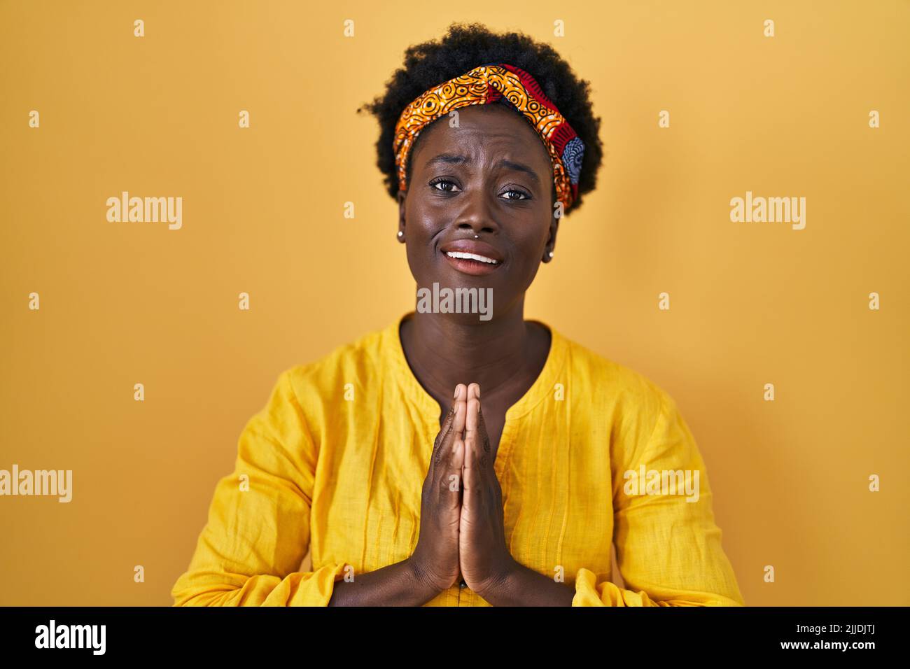 African young woman wearing african turban begging and praying with ...