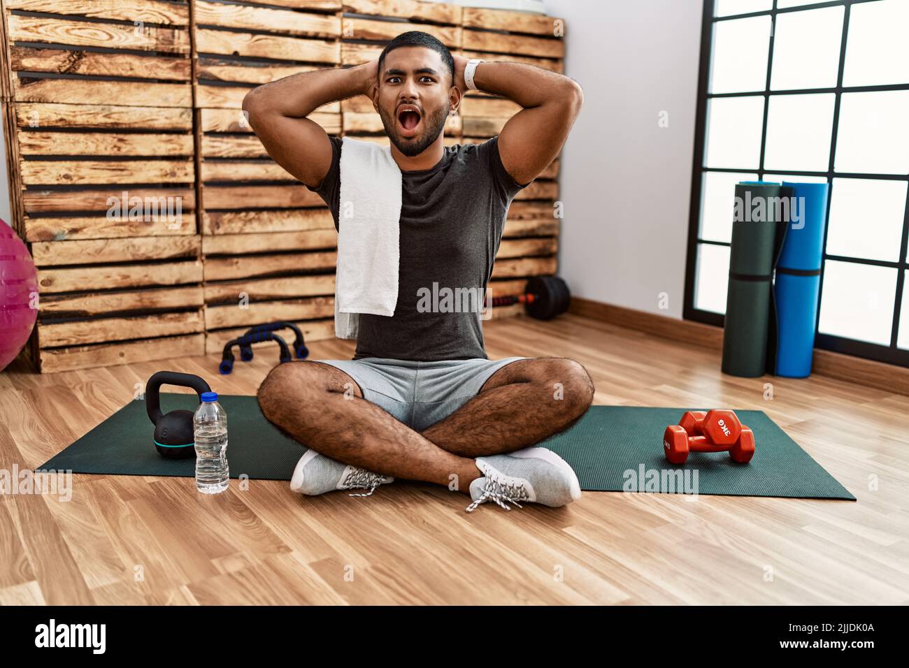 Young indian man sitting on training mat at the gym crazy and scared ...