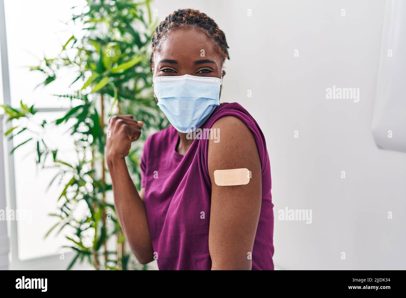 Beautiful black woman getting vaccine showing arm with band aid ...