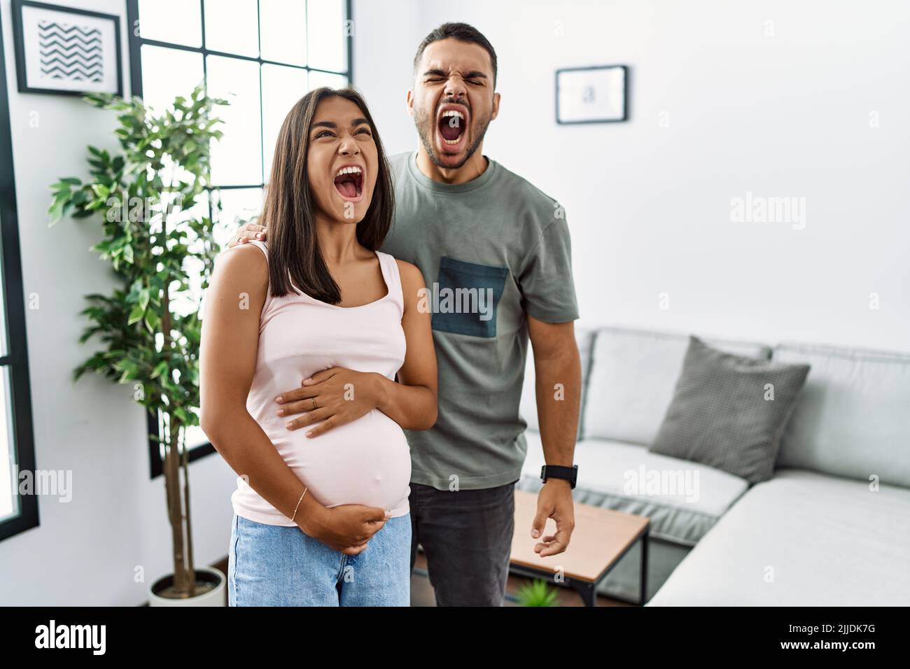 Young interracial couple expecting a baby, touching pregnant belly ...