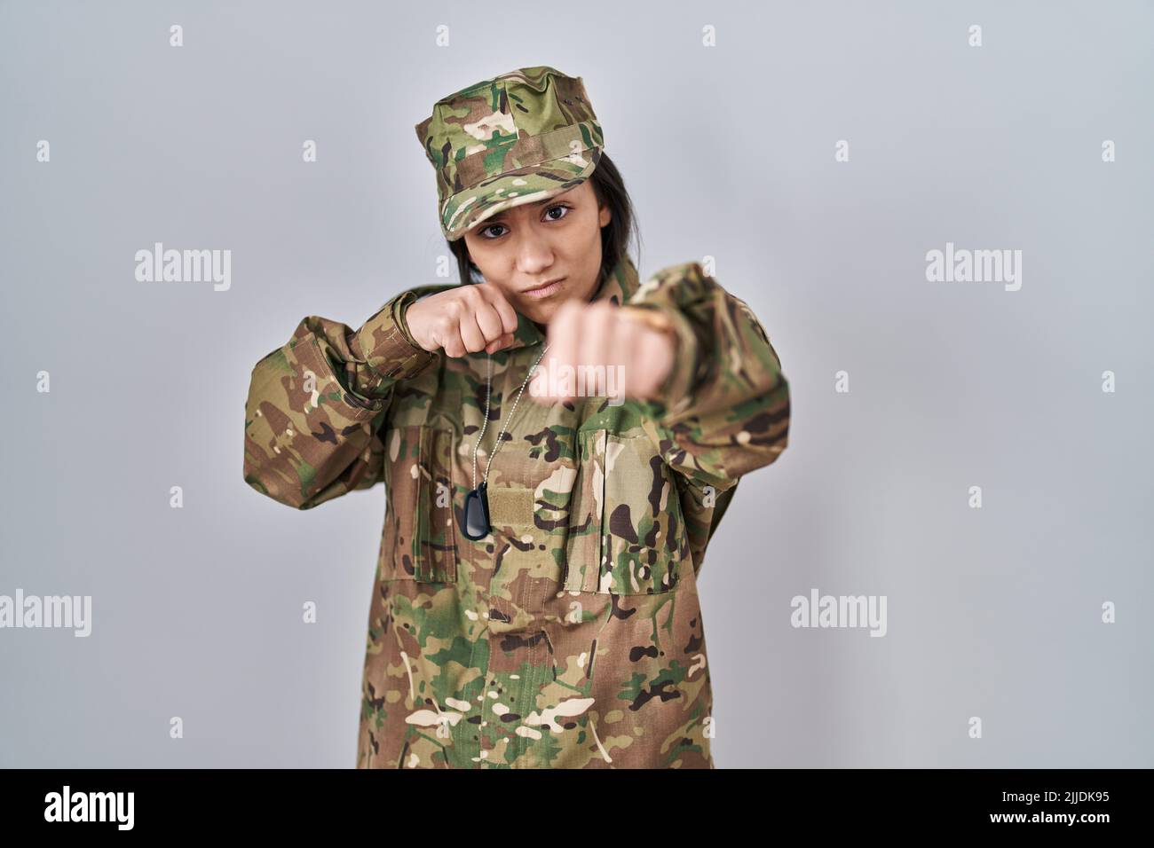 Young south asian woman wearing camouflage army uniform punching fist ...