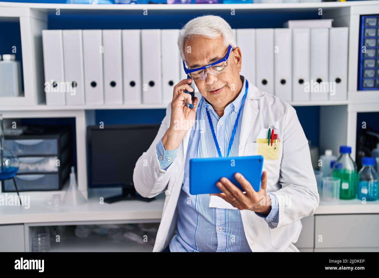 Senior man scientist using touchpad talking on the smartphone at laboratory Stock Photo - Alamy