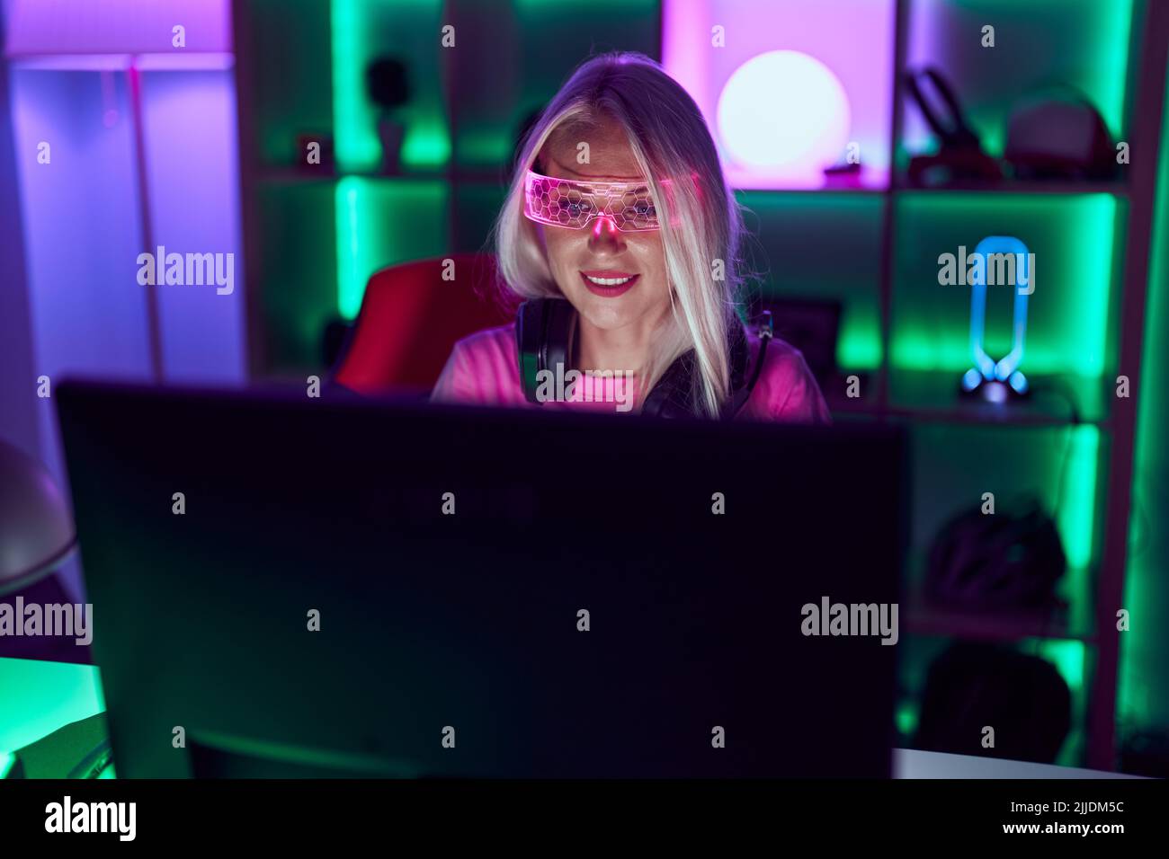 Young blonde woman streamer using computer and virtual reality glasses ...