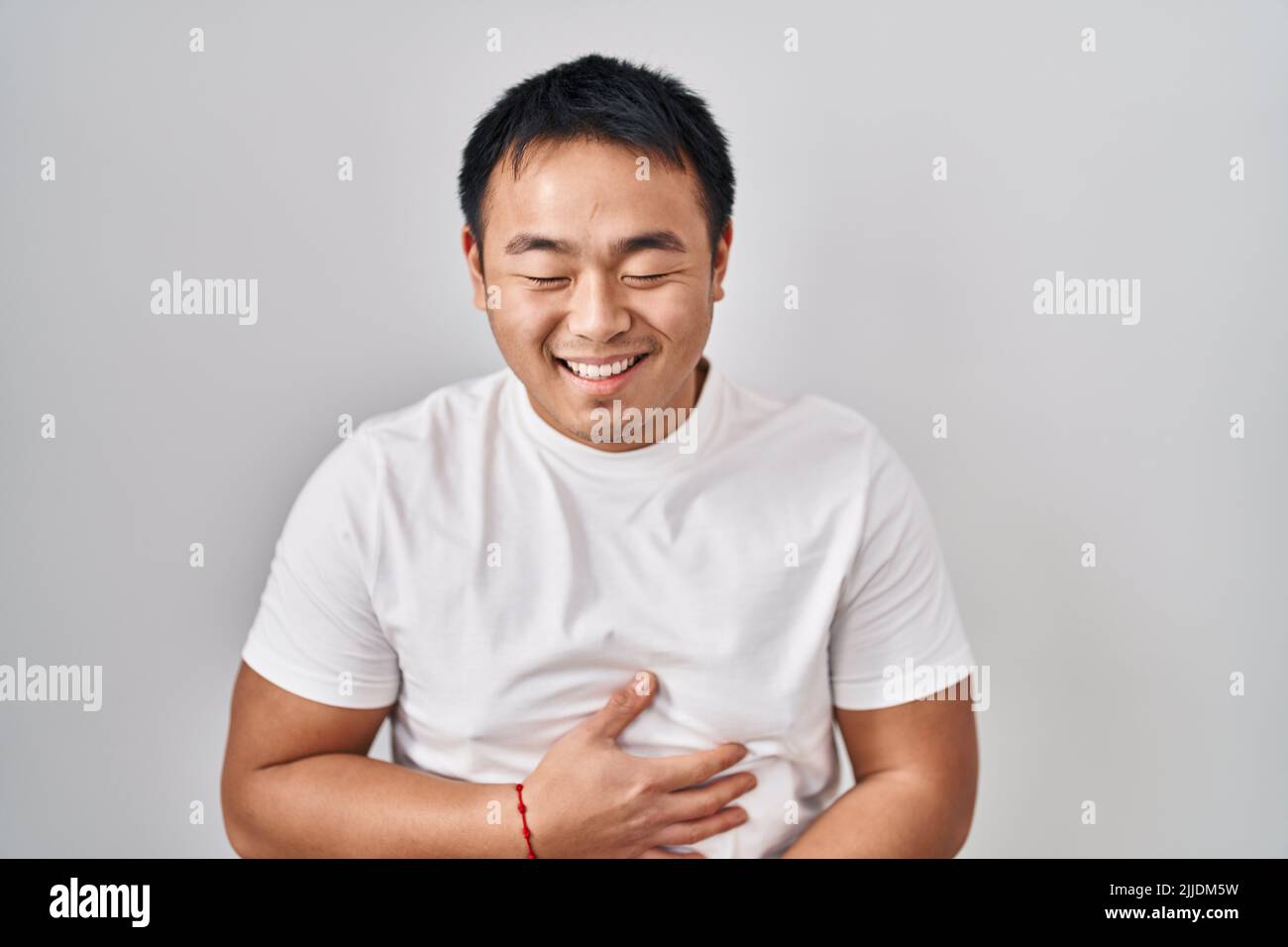 Young Chinese Man Standing Over White Background Smiling And Laughing Hard Out Loud Because