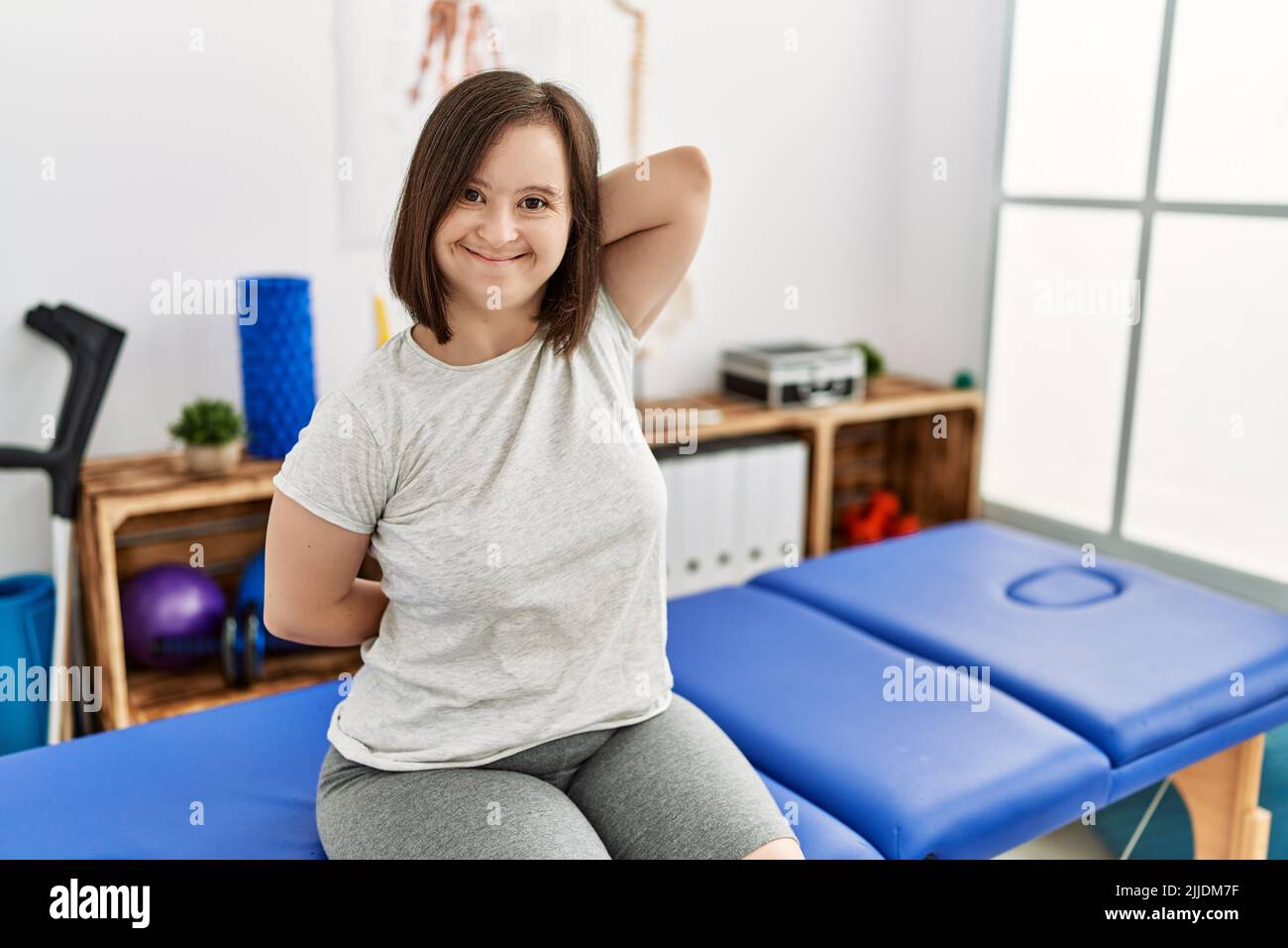 Brunette woman with down syndrome stretching arms at physiotherapy ...