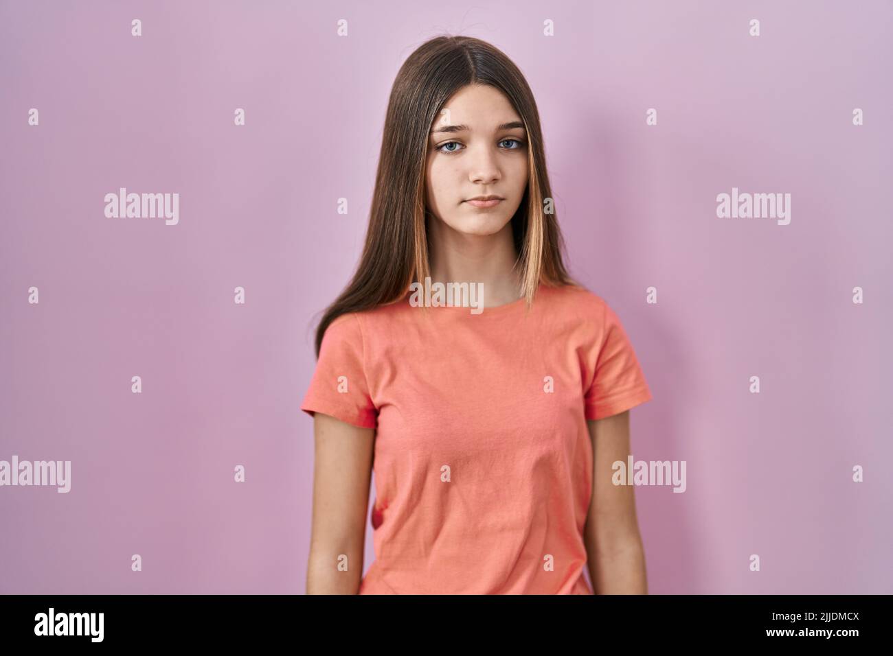 Teenager girl standing over pink background looking sleepy and tired ...