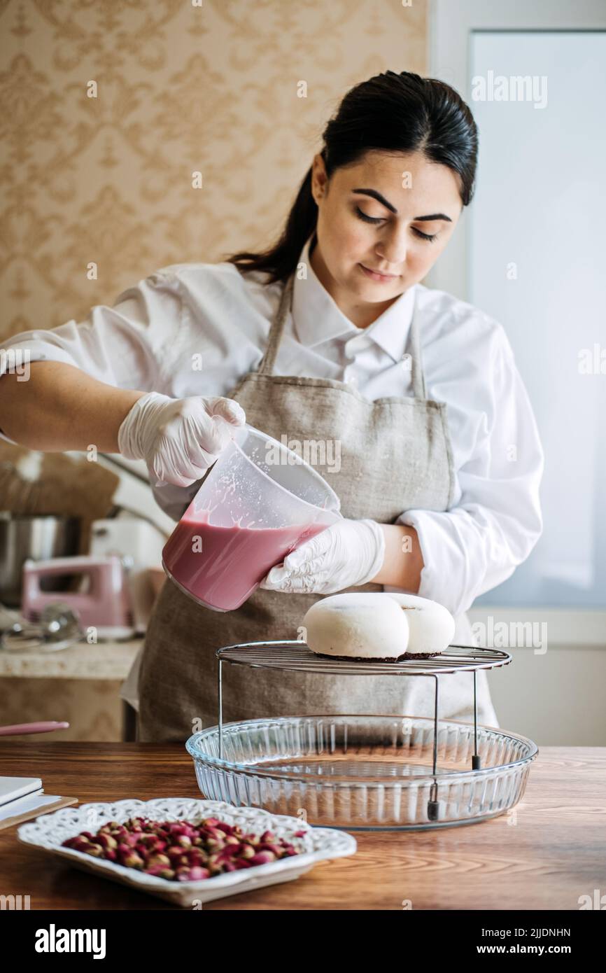 Mousse heart shape pink cake in hand of Asian Arabic woman pastry chef ...
