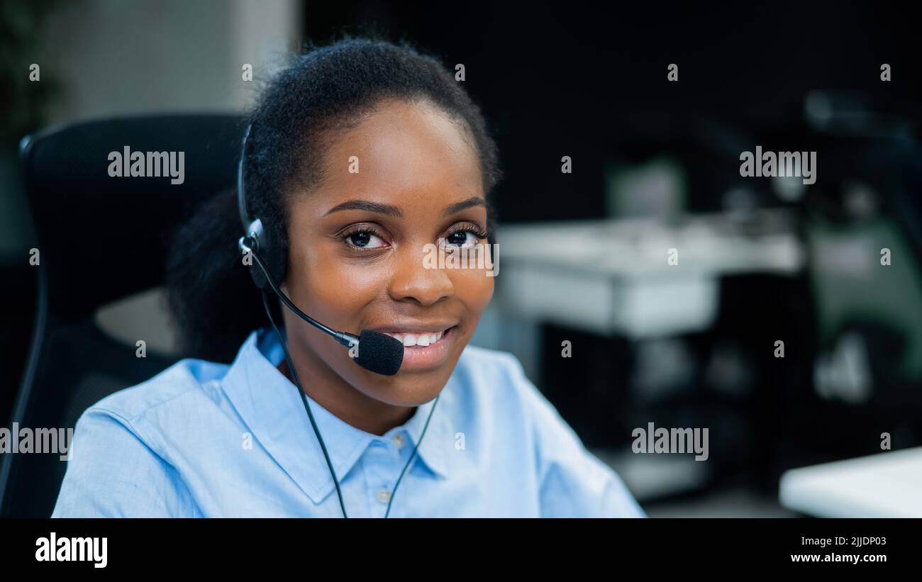 African young woman talking to a client on a headset. Female employee ...