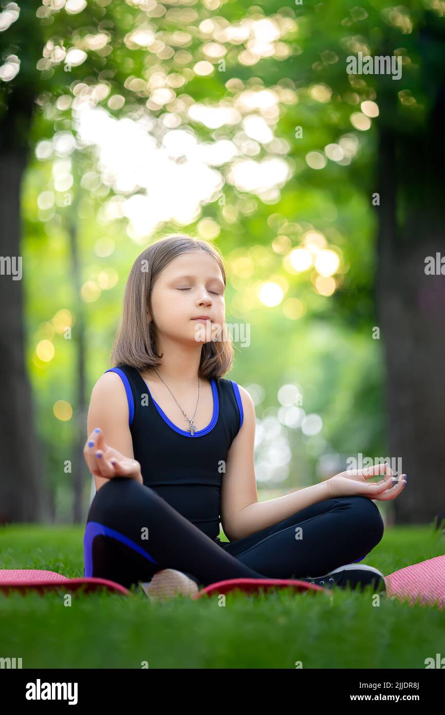 meditation in the park in the lotus position little girl meditates and ...