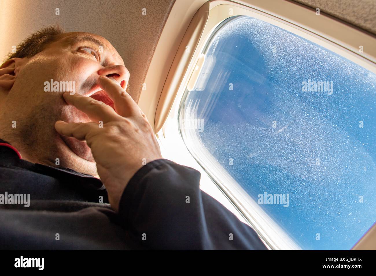 Scared man looks out the window of a flying plane Stock Photo - Alamy