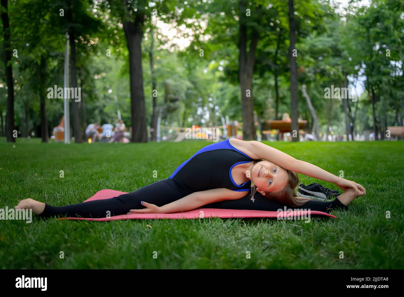 a girl in the park stretches Nogina Ida in the side and holds out her ...
