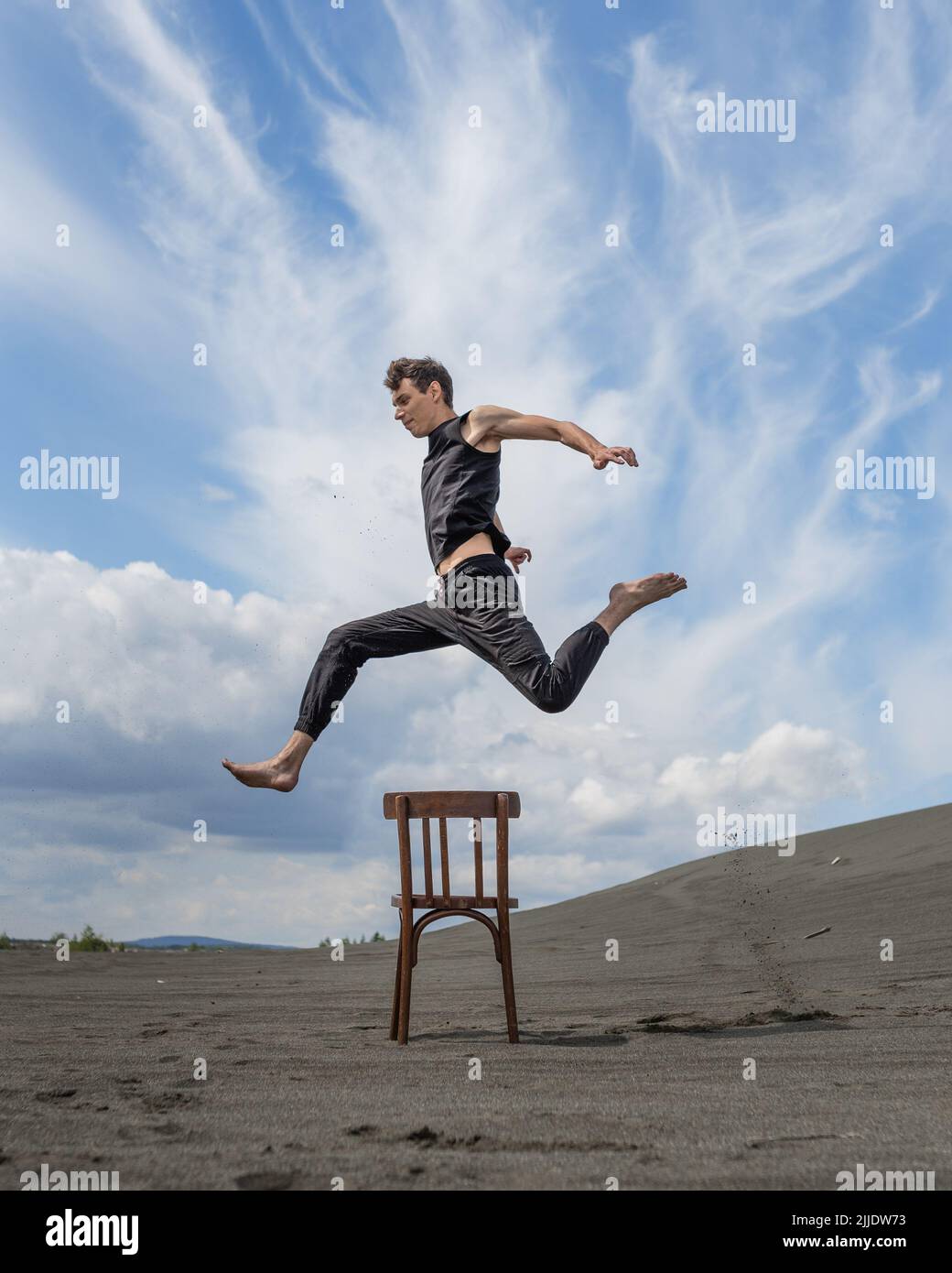 Man jumping over chair in sand desert Stock Photo - Alamy