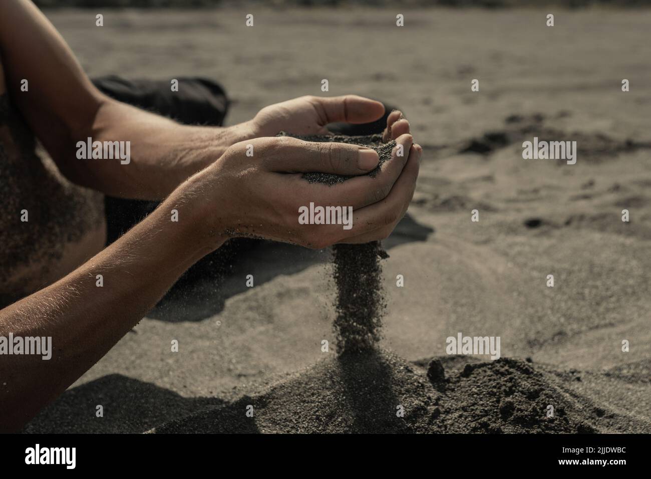 Man pouring sand through hands in the desert Stock Photo - Alamy
