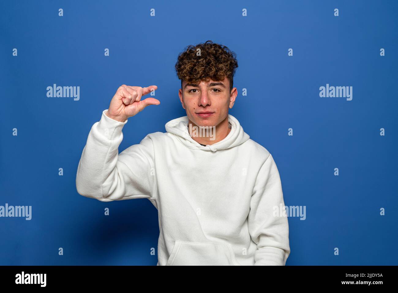 Unhappy young man looking disappointed and showing a small gesture, a ...