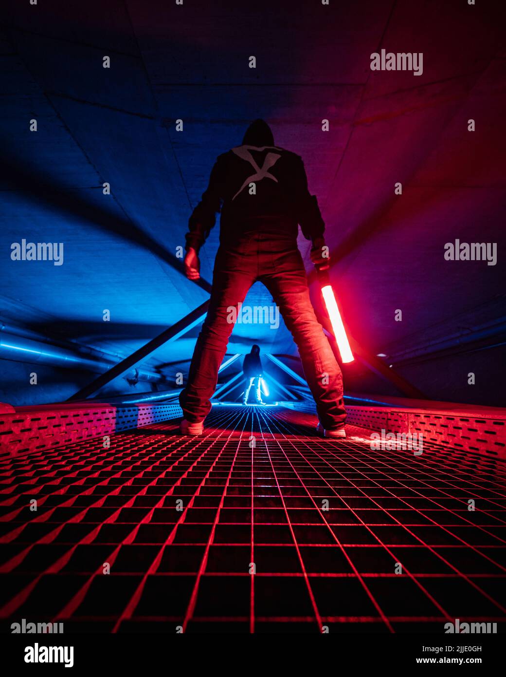 A dramatic shot of two rivals in a standoff using light swords in red ...